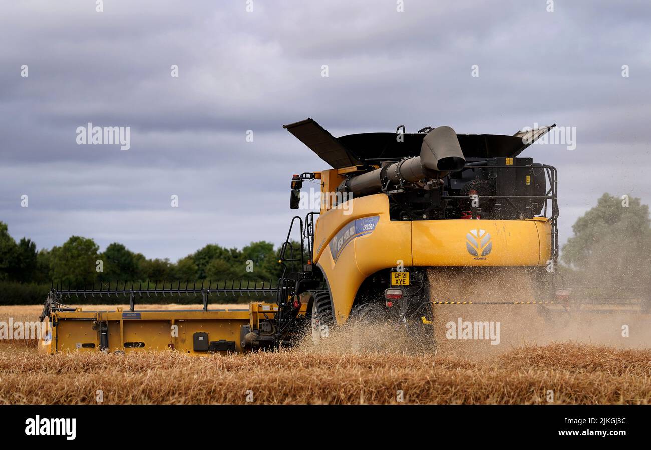 A combine harvester at work in a field near Brenzett in Kent, as the ...