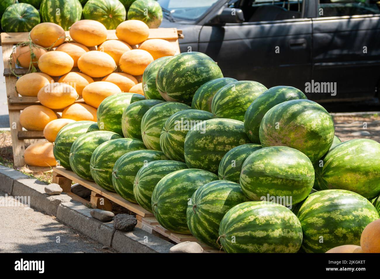 Ripe melons and watermelons lie on the counter in a street market. Food ...