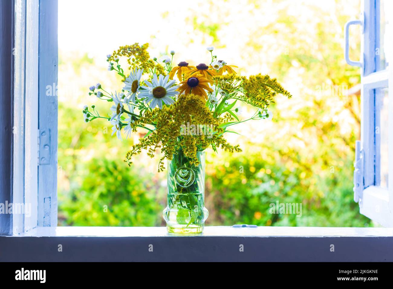 a beautiful bouquet of wildflowers on the windowsill at an open window ...