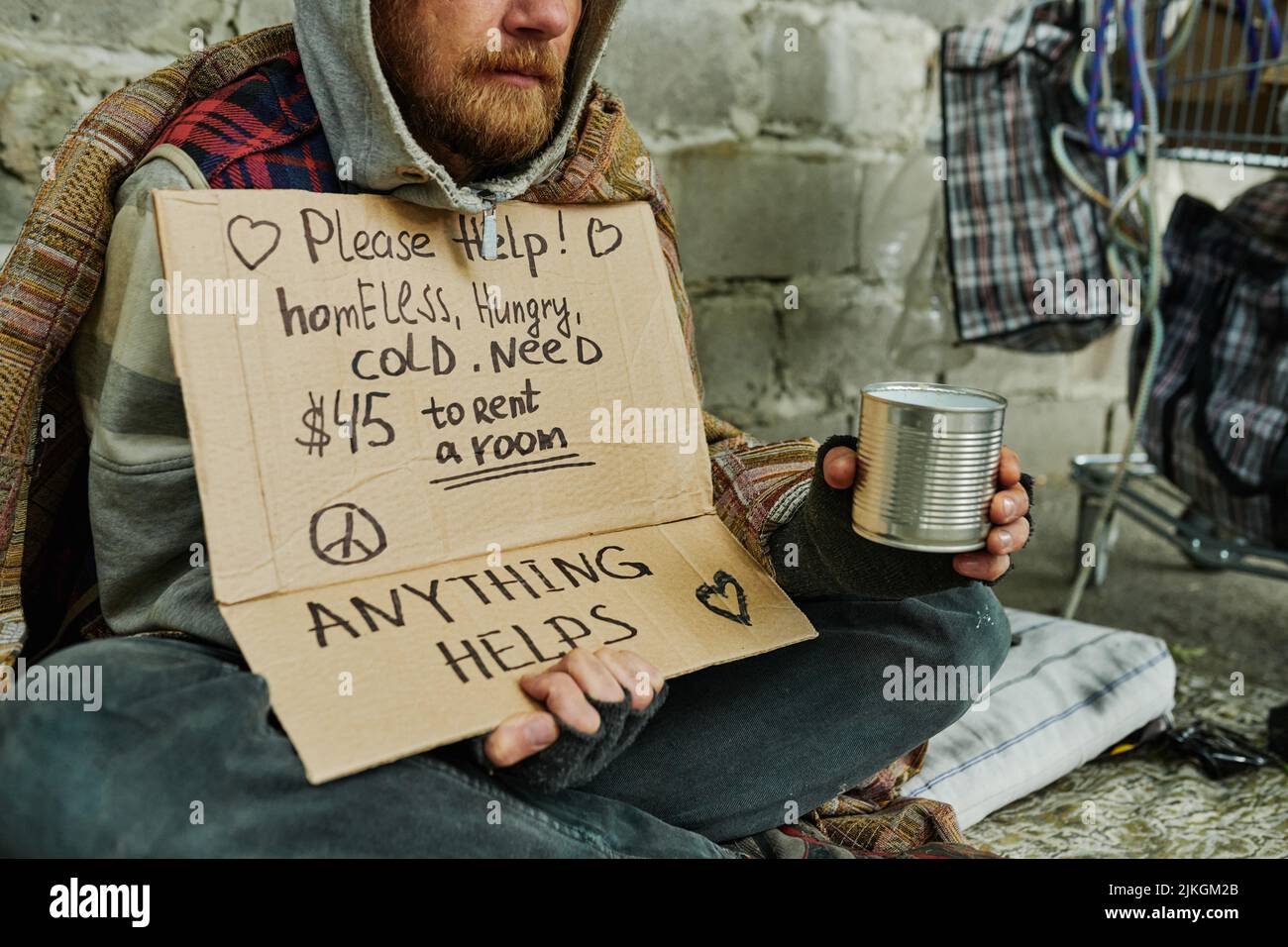 Close-up of poor man sitting on the ground outdoors with poster and ask ...