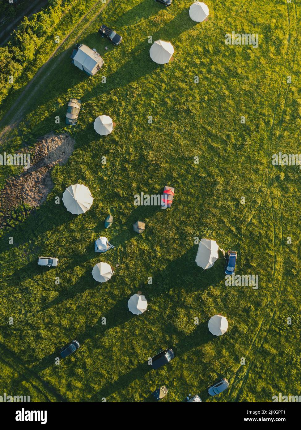 A vertical aerial view of an idyllic campsite with bell tents in a ...