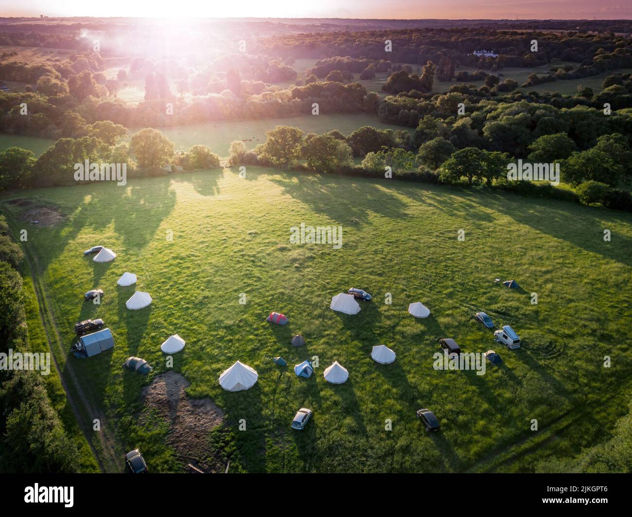 An aerial view of an idyllic campsite with bell tents and cars in a ...