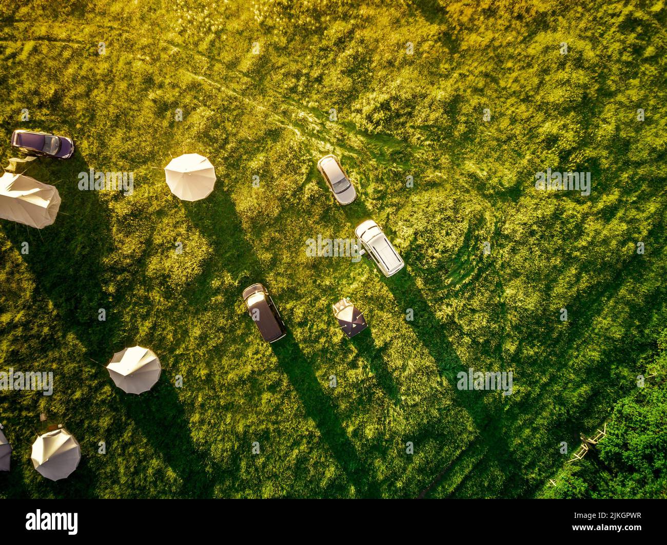 An aerial view of an idyllic campsite with bell tents and cars in a ...