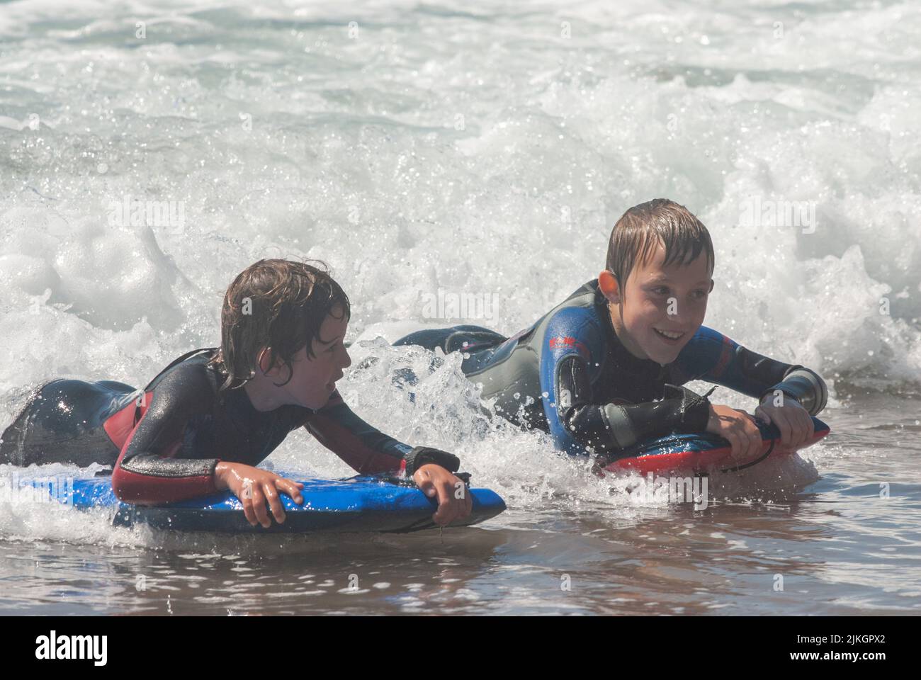 Two boys boogie boarding at West Dale beach, Pembrokeshire, Wales, UK ...