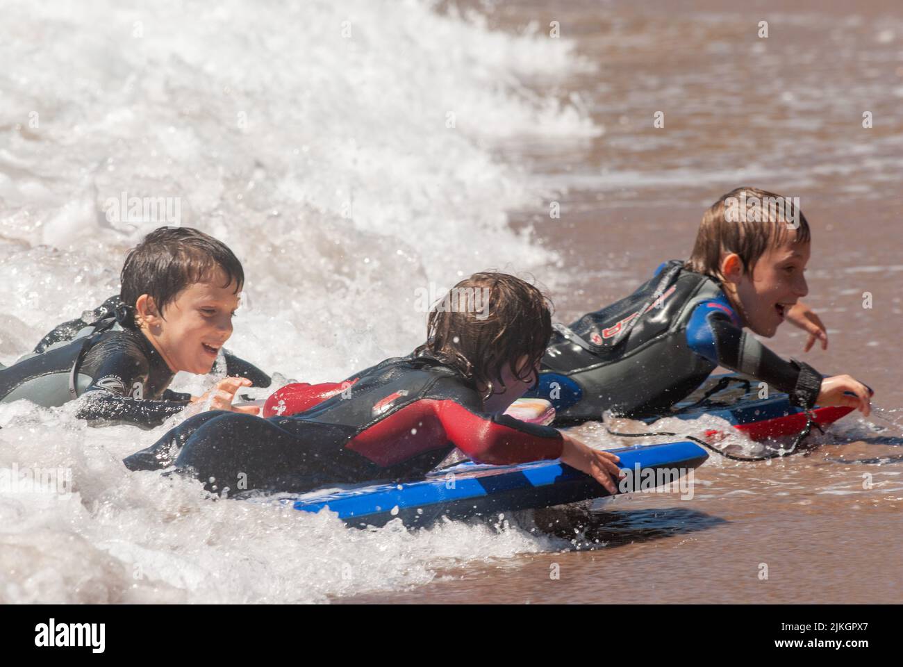 Two boys boogie boarding at West Dale beach, Pembrokeshire, Wales, UK ...