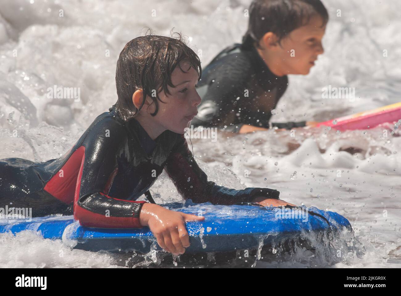 Two boys boogie boarding at West Dale beach, Pembrokeshire, Wales, UK ...