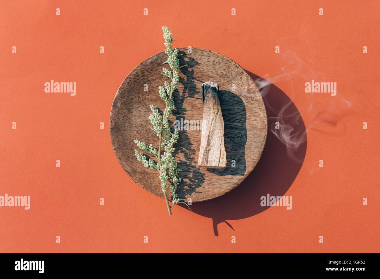 Burning palo santo stick with smoke on wooden stand over red orange ...