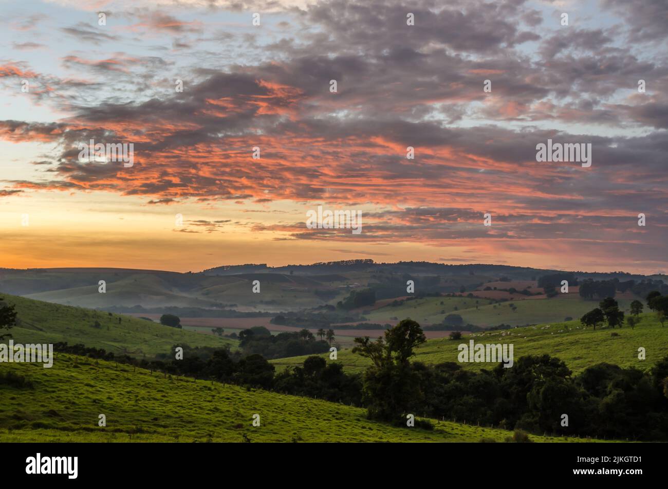A scenic countryside landscape with fields and mountains during sunset ...