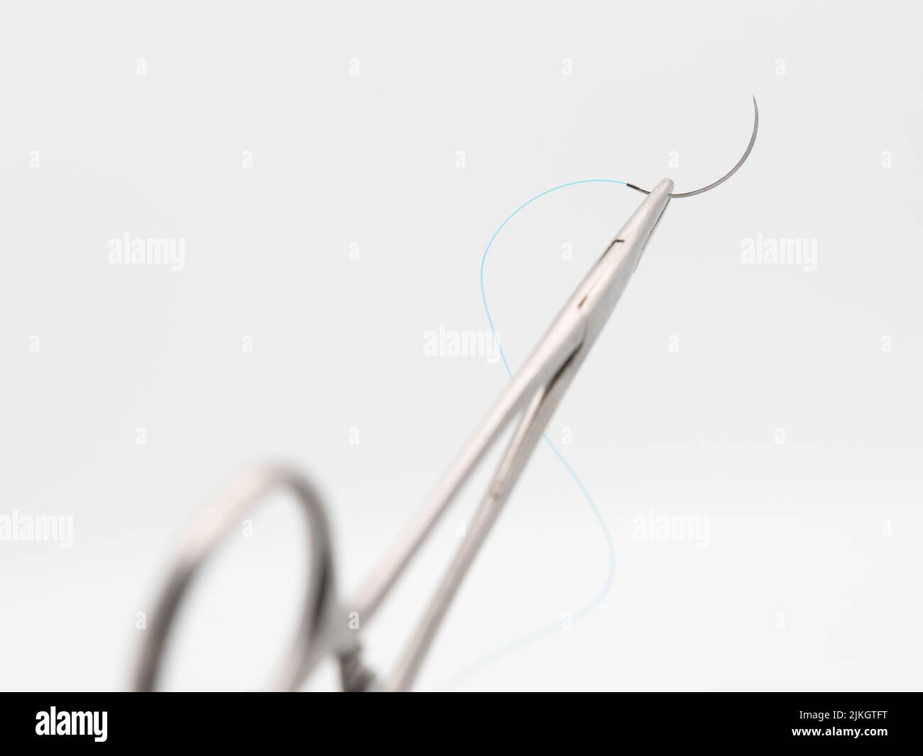 A surgical needle and thread on suture scissors isolated on a white ...