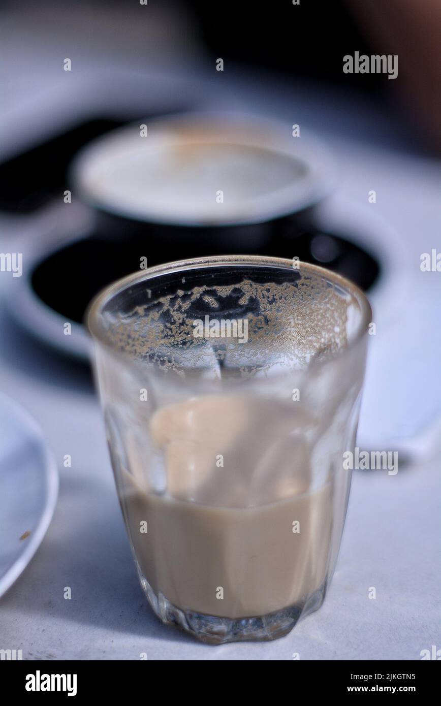 A vertical closeup of a half-drunk glass of coffee with milk Stock ...