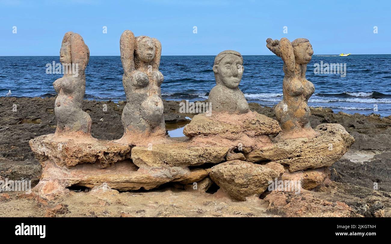 A view of stony human sculptures in beach in background of sea Stock ...