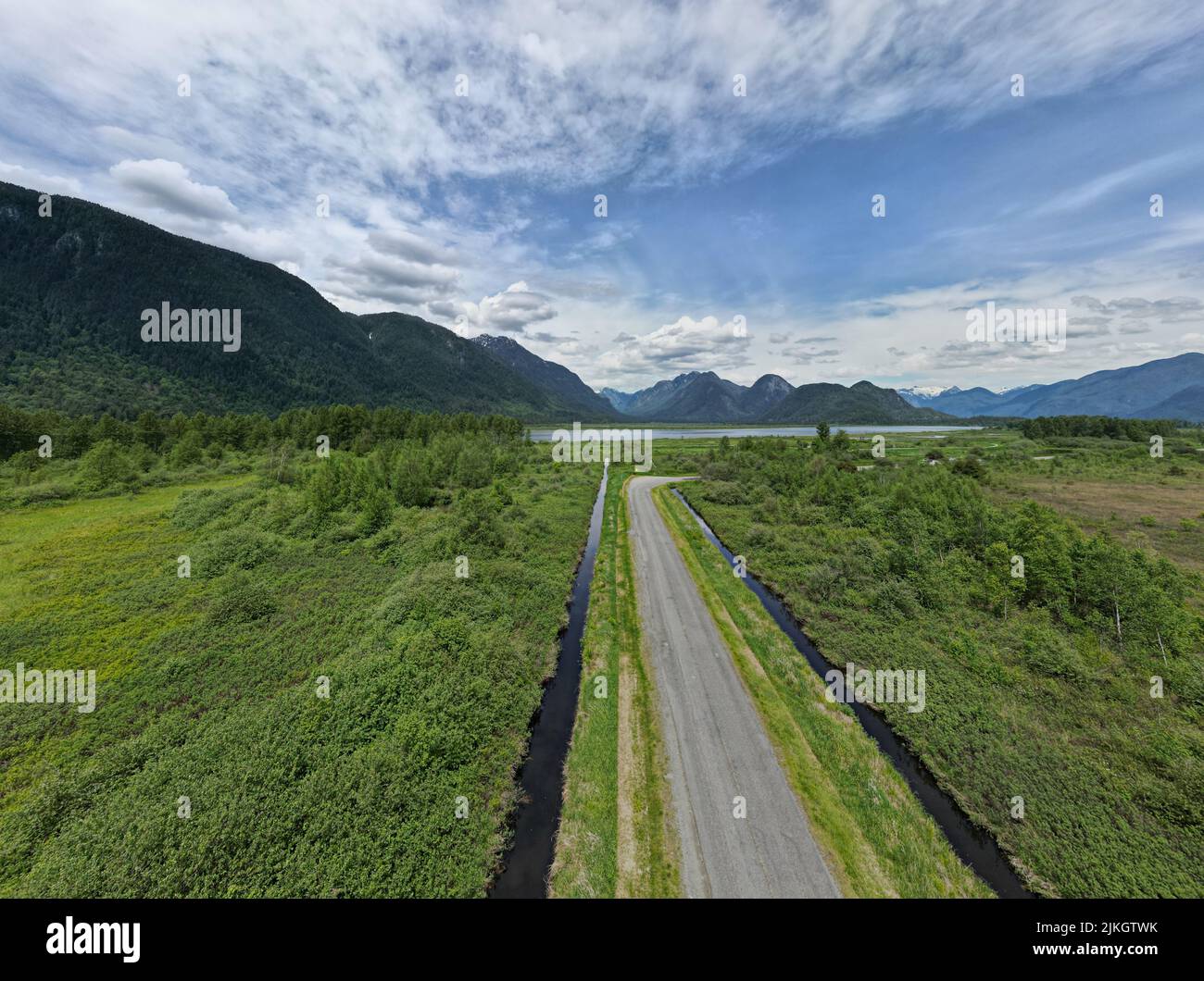 A high angle shot of an empty asphalt road in a green field against a ...