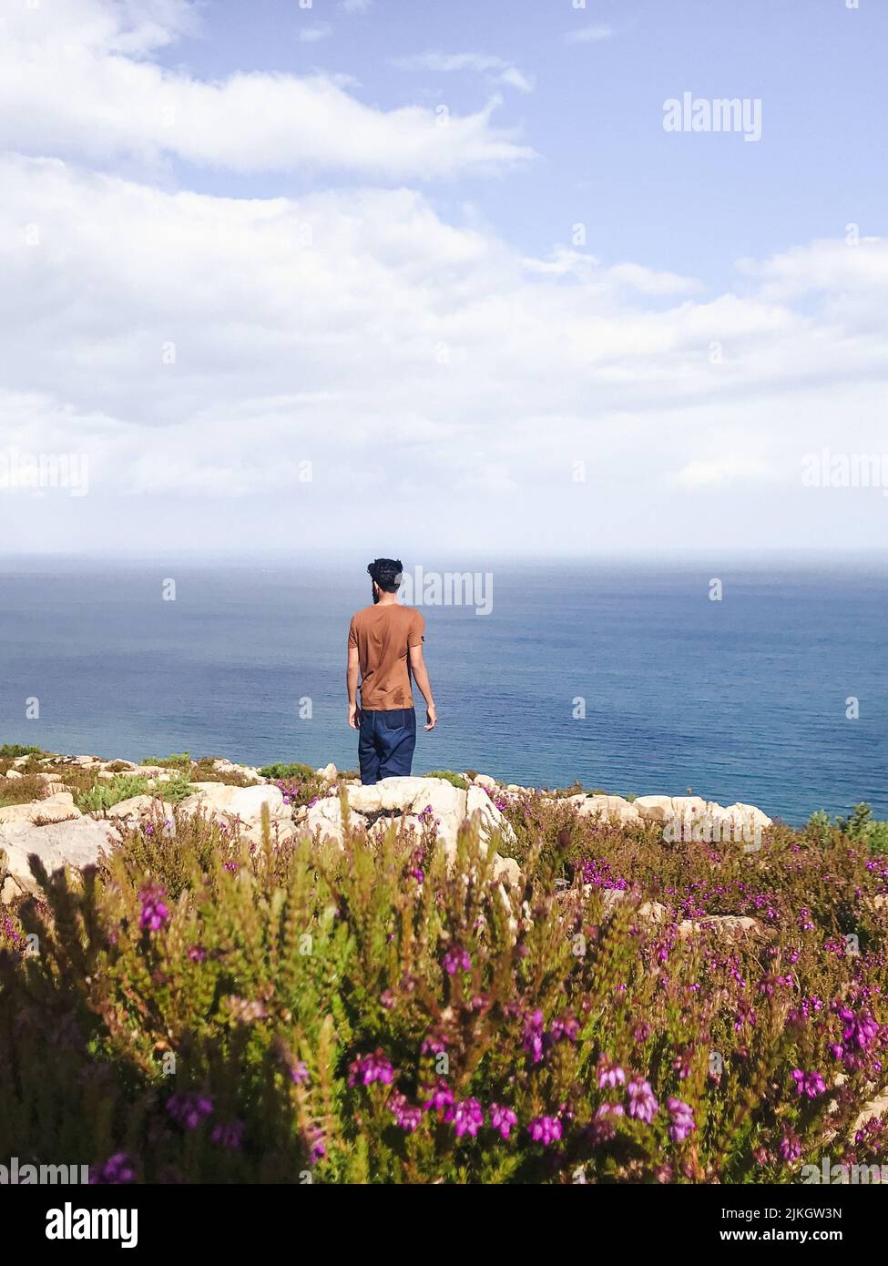 A portrait of a male standing on top of a cliff overlooking the horizon ...