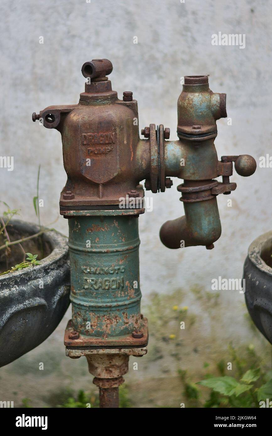 A vertical closeup of an old rusty water pump in Bandung, Indonesia ...