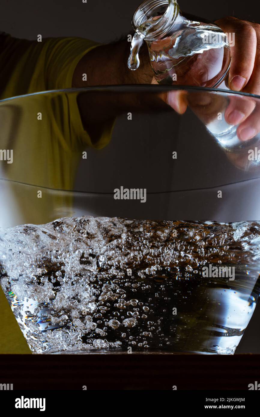 A closeup of a male pouring clean water into a glass bowl Stock Photo ...