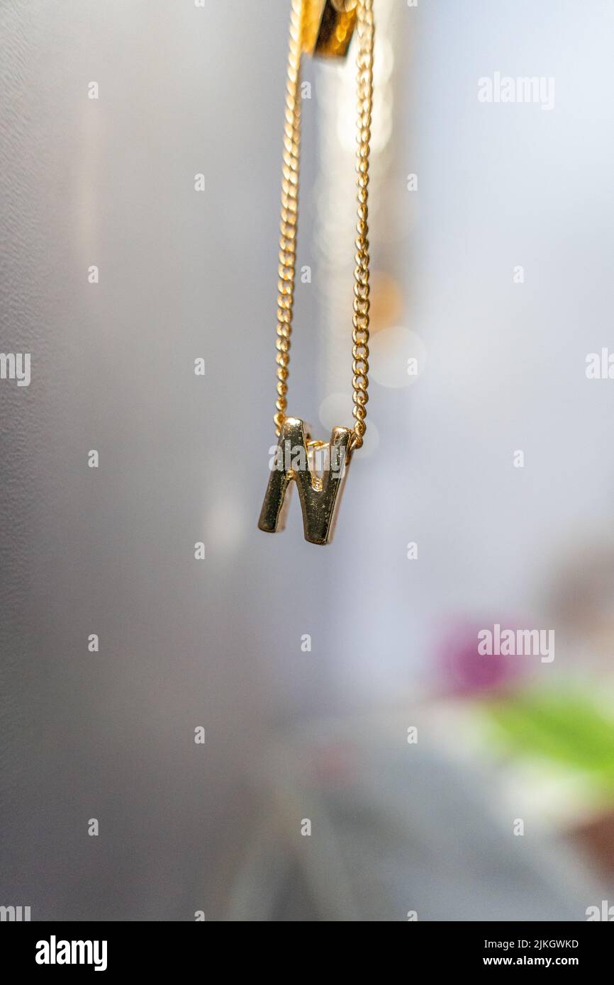 A vertical closeup of the golden chain with the N letter against the ...