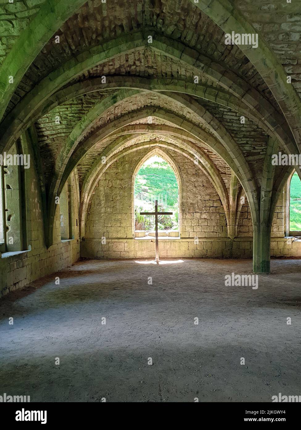 A cross in front of a window of an ancient building with arch ceiling ...