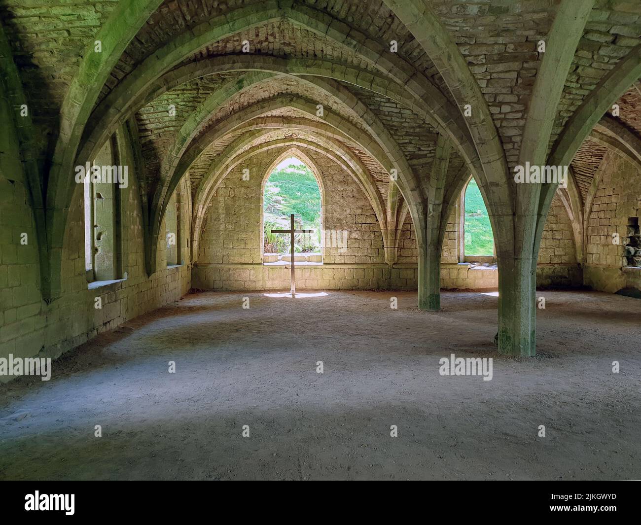 A cross in front of a window of an ancient building with arch ceiling ...