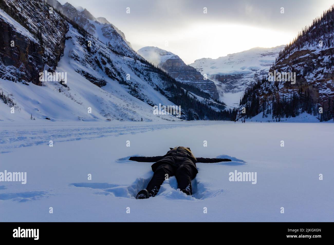A human lying on snow in background of huge snow covered mountains in ...