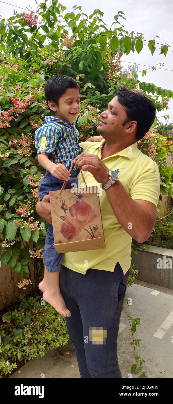 Front view of father with his little boy who is holding gift bag for ...