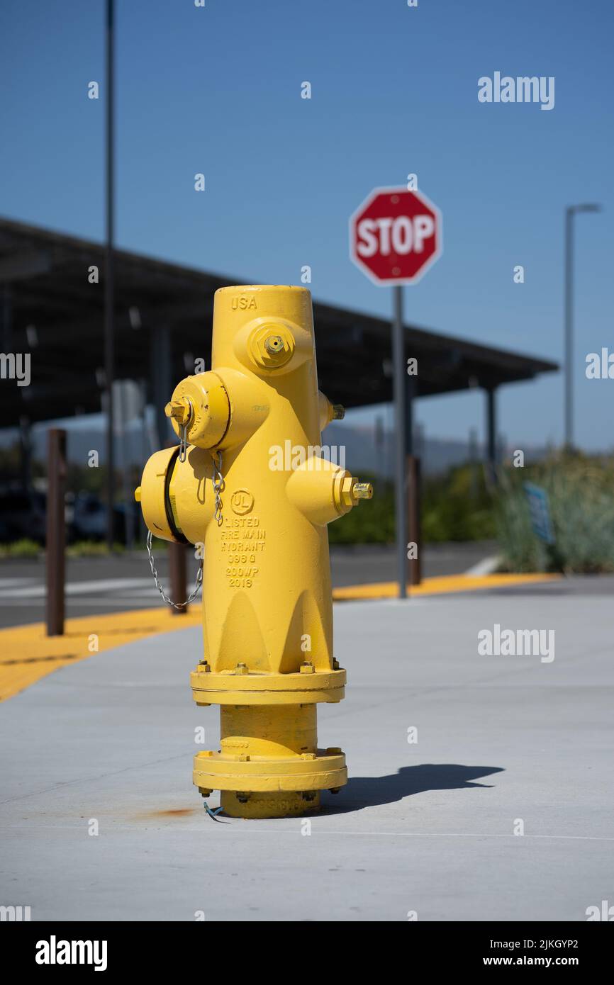 A vertical shot of a yellow fire hydrant in the street with a stop sign ...