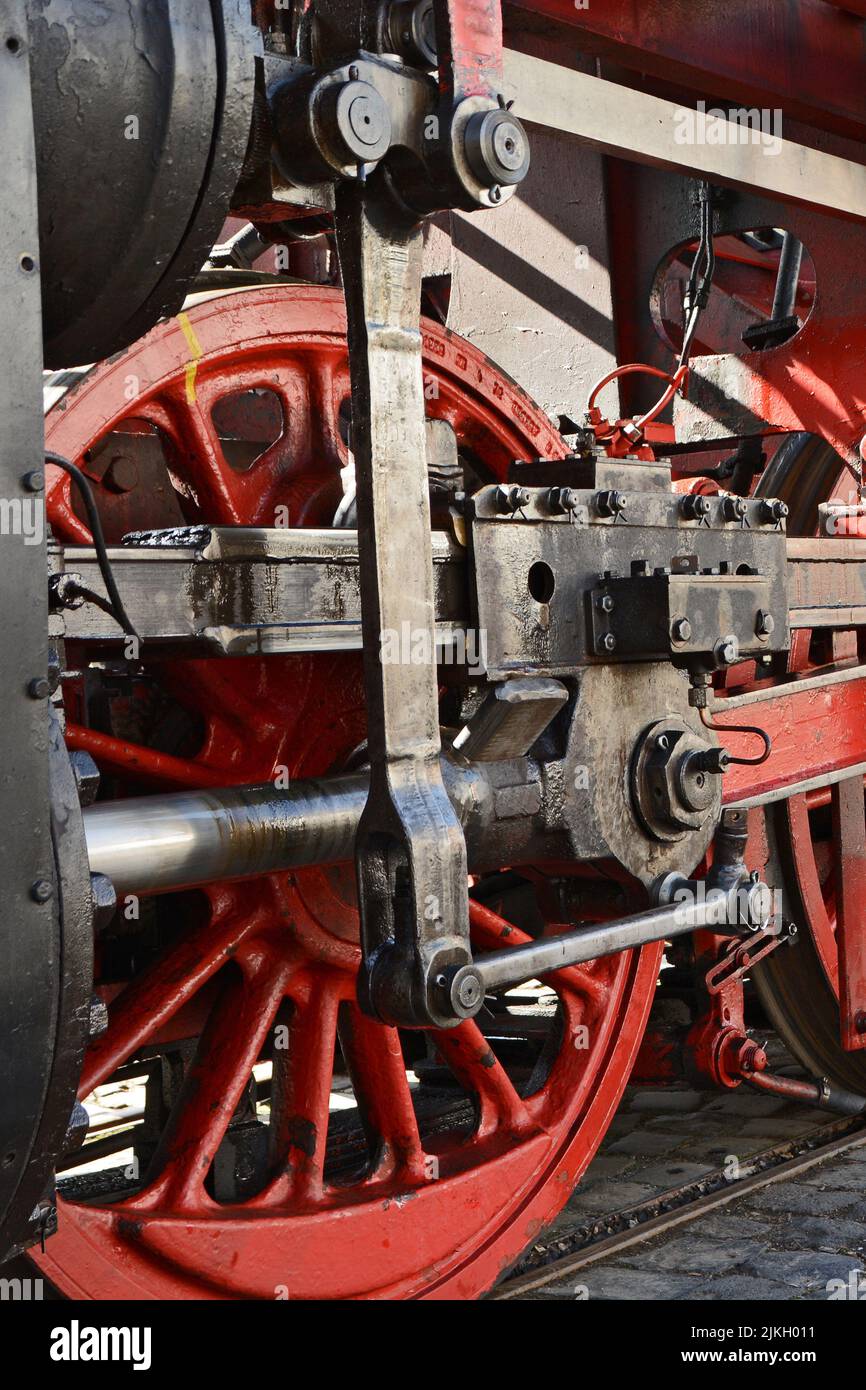 The red painted wheels of a steam locomotive on the railroad tracks ...