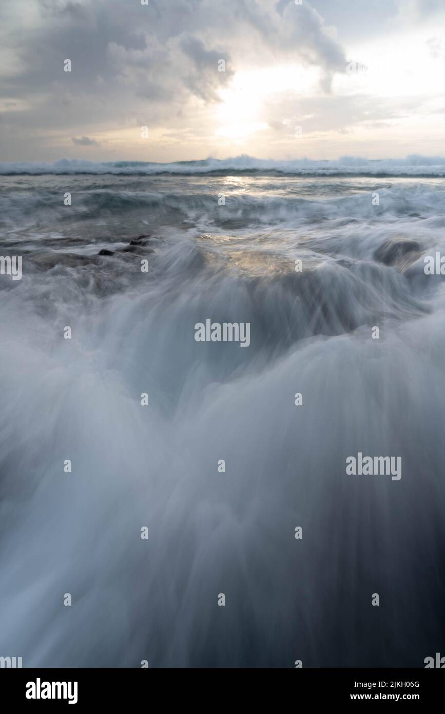 The vertical shot of sea waves foam touching the wet stones, vertical ...
