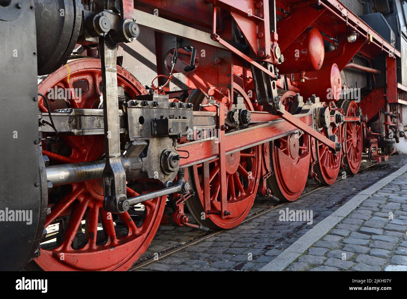 The red painted wheels of a steam locomotive on the railroad tracks ...