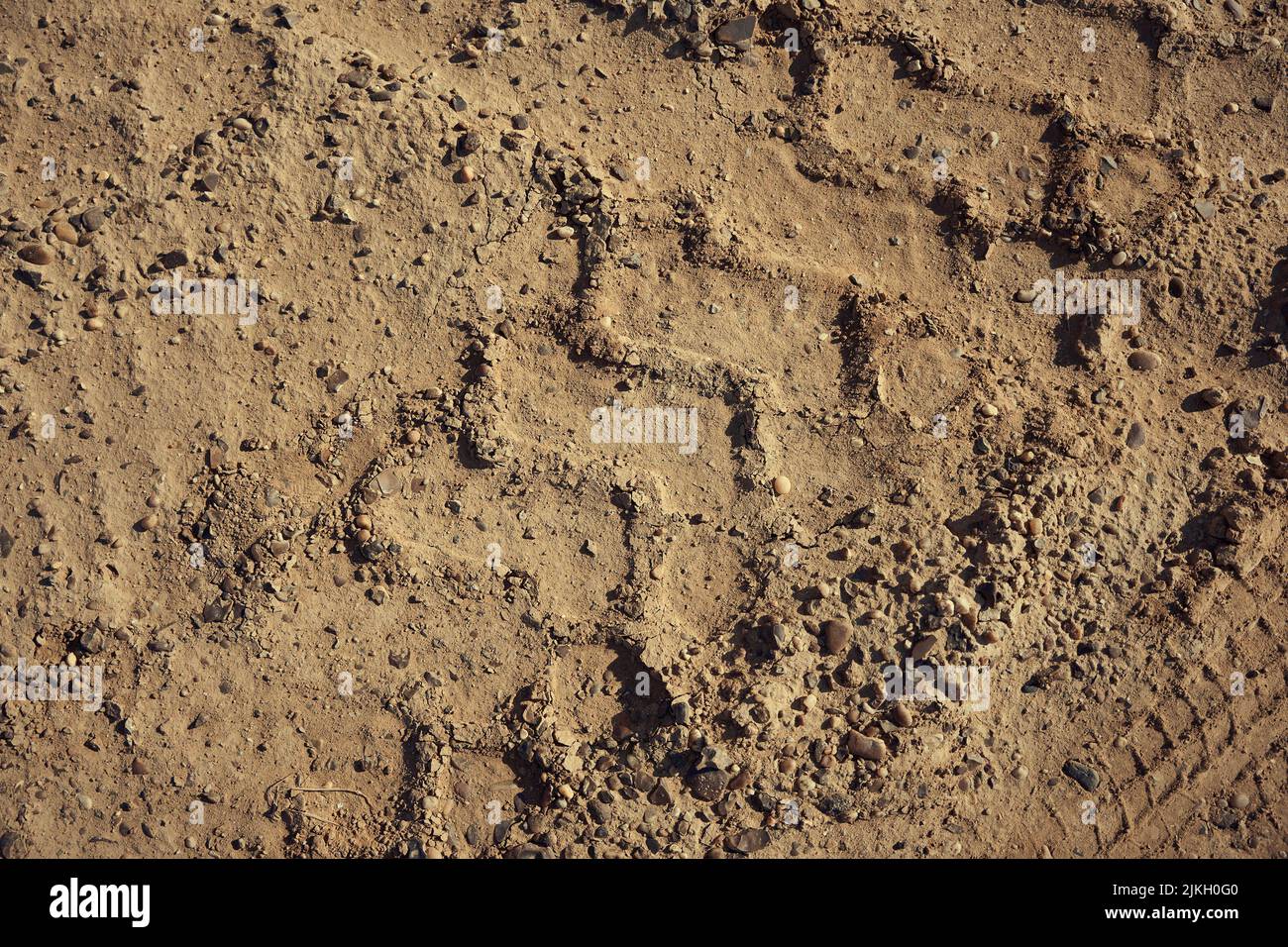 A dirt gravel road with tire tracks texture at the construction site ...