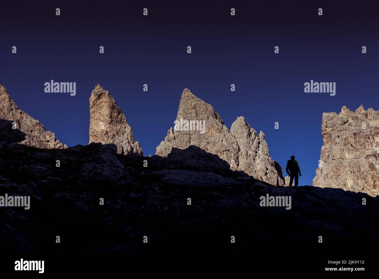 Lonely mountaineer silhouetted with awesome dolomite ridges background ...