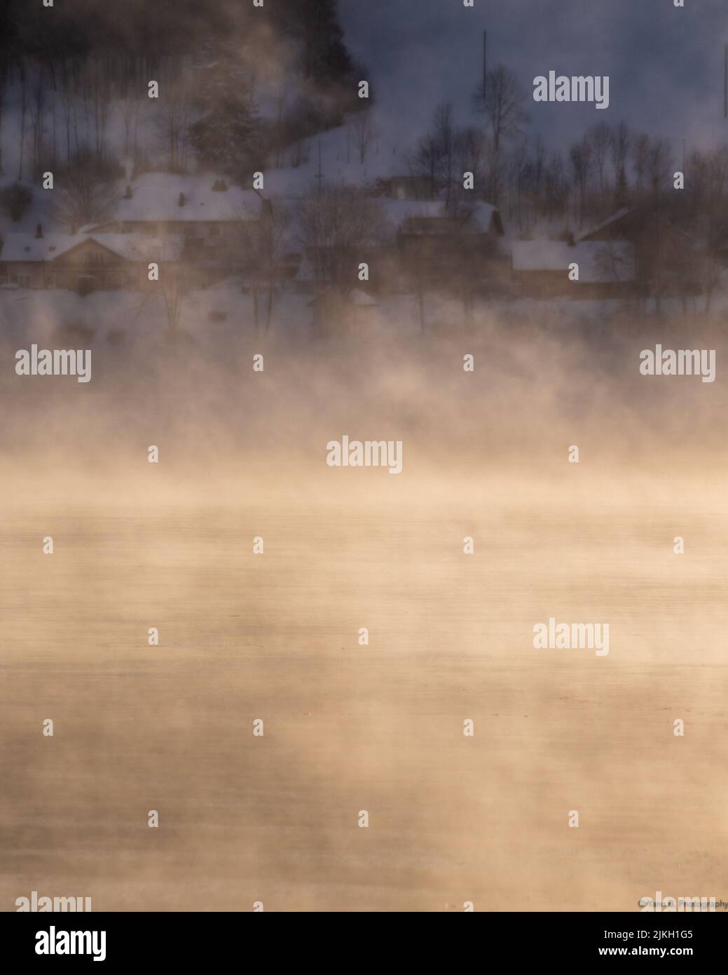 A vertical shot of the Lac de Joux lake covered with mist and smog in ...