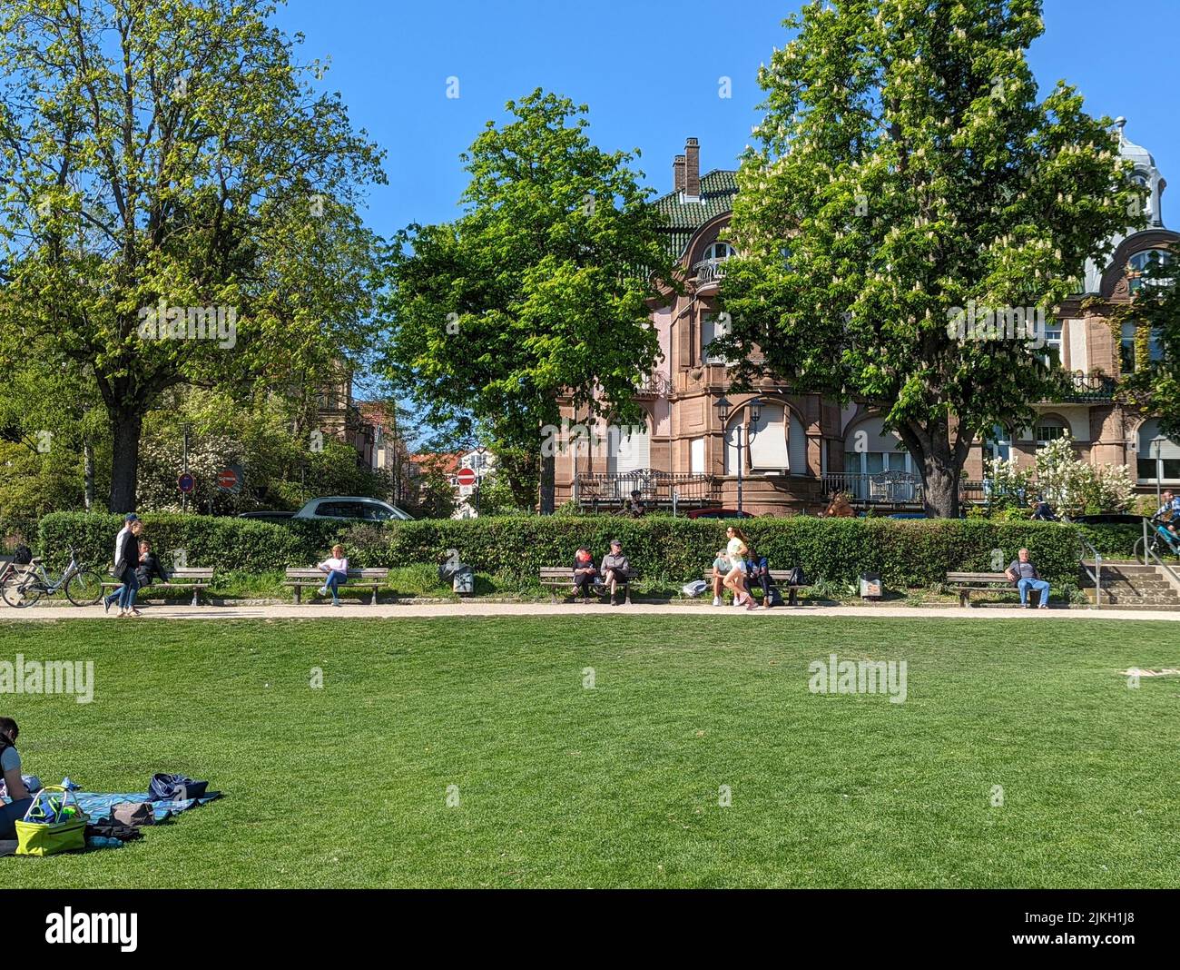 The people having a rest or jogging against villas and a tree avenue in ...
