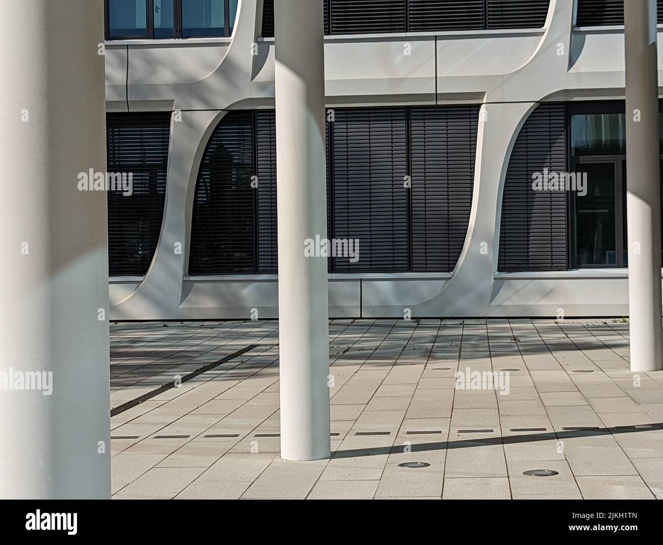 An exterior of a modern white office building with columns and large ...