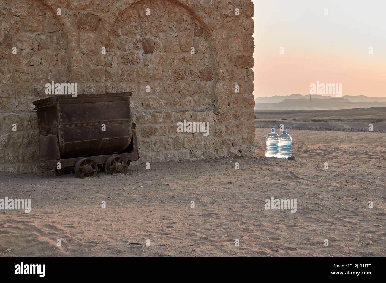 A view of two water cisterns near a stone building and a rusty cart ...