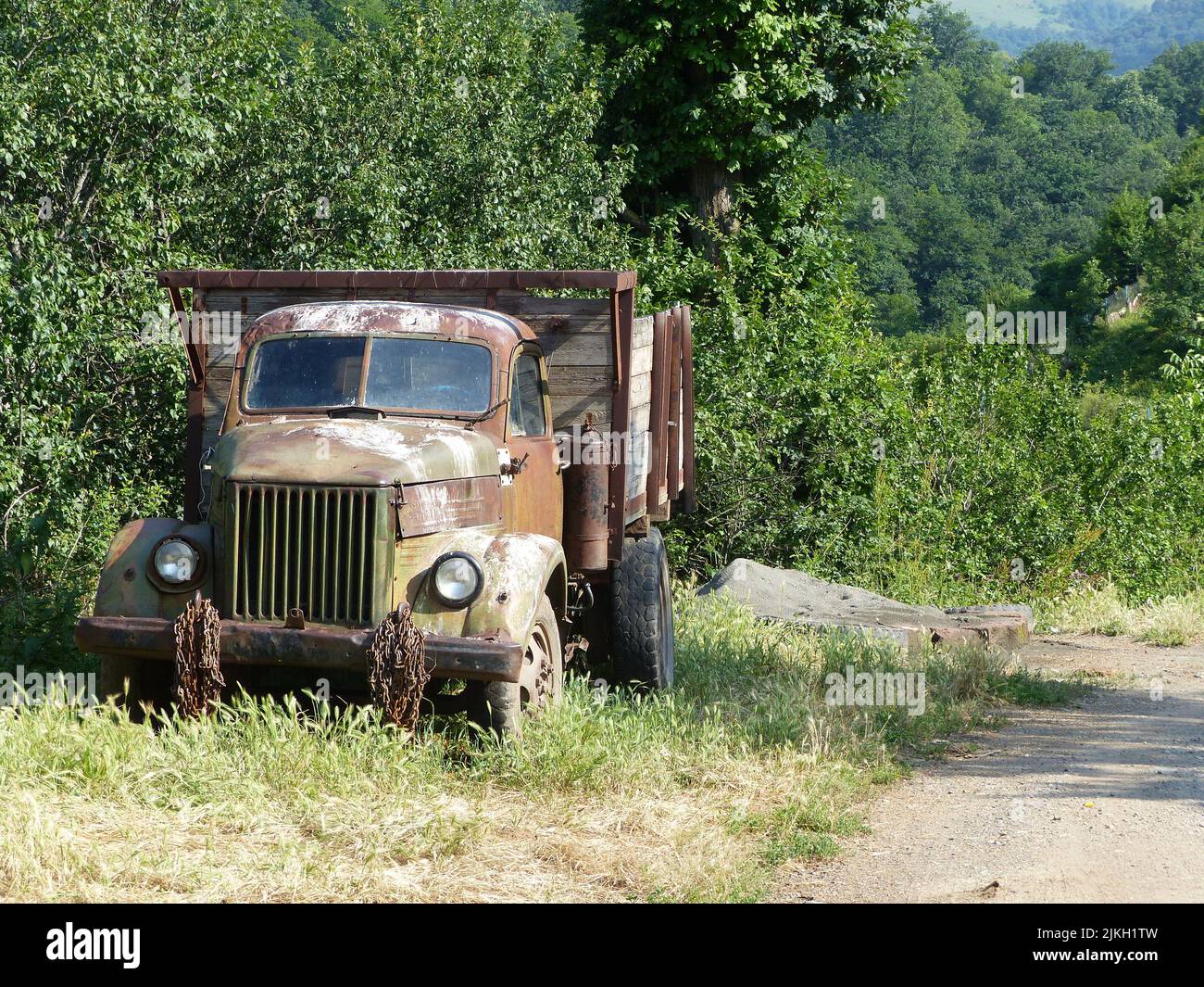 An old GAZ truck parked off the road with a view of forest in the ...