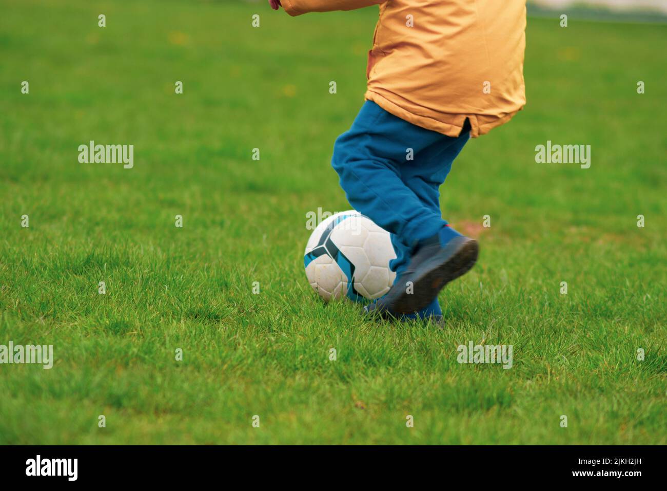 A child playing with a soccer ball on a green field Stock Photo - Alamy