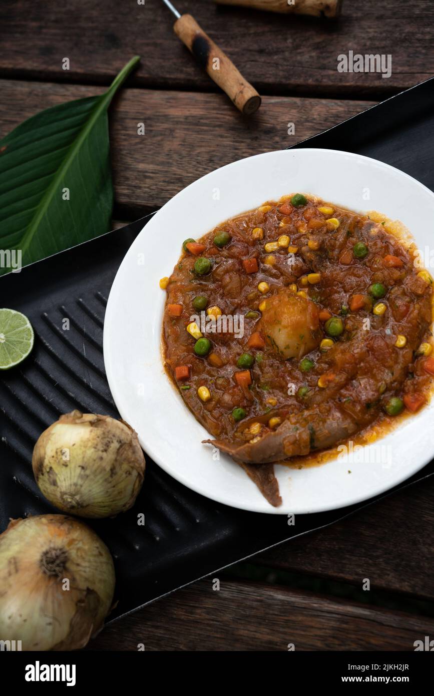 A vertical high angle shot of a bowl of vegetable stew with corn and ...