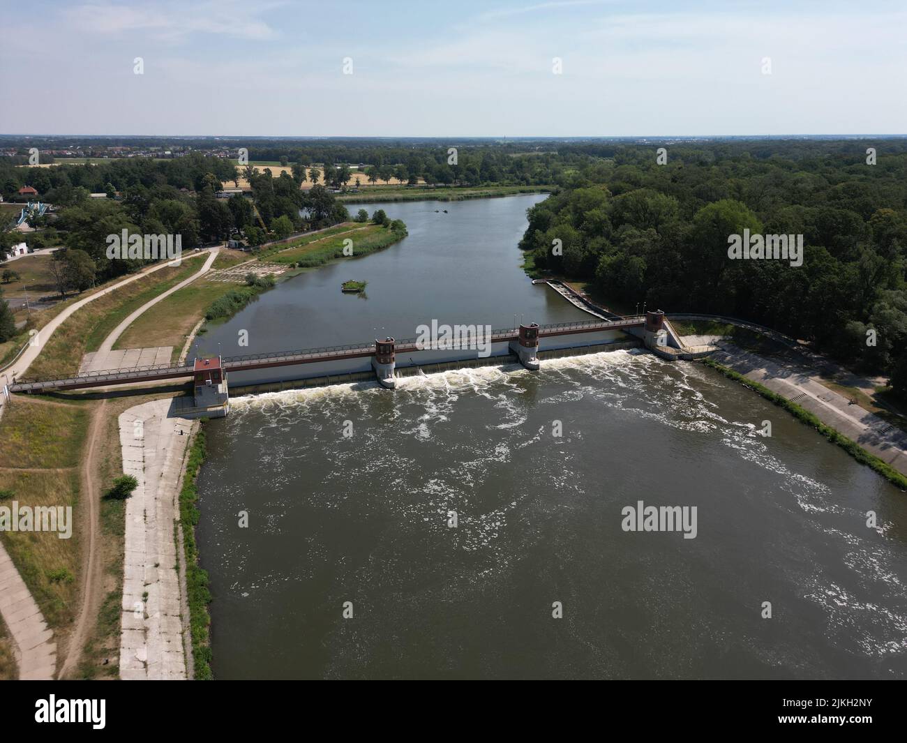 An aerial view of a bridge over a damn canal with a forest in the ...