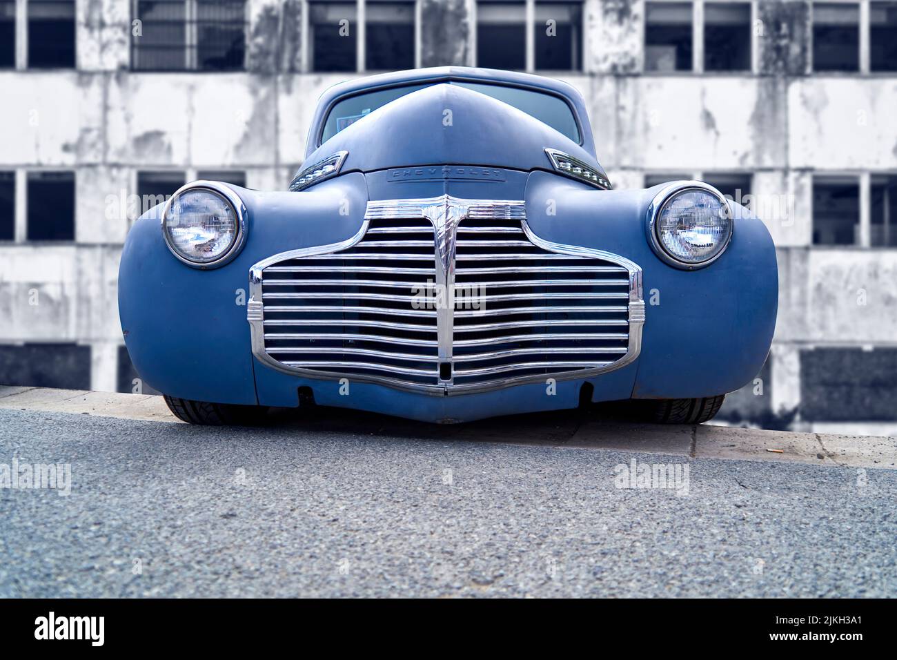 Chevrolet classic car in matte blue color in front of old destroyed ...