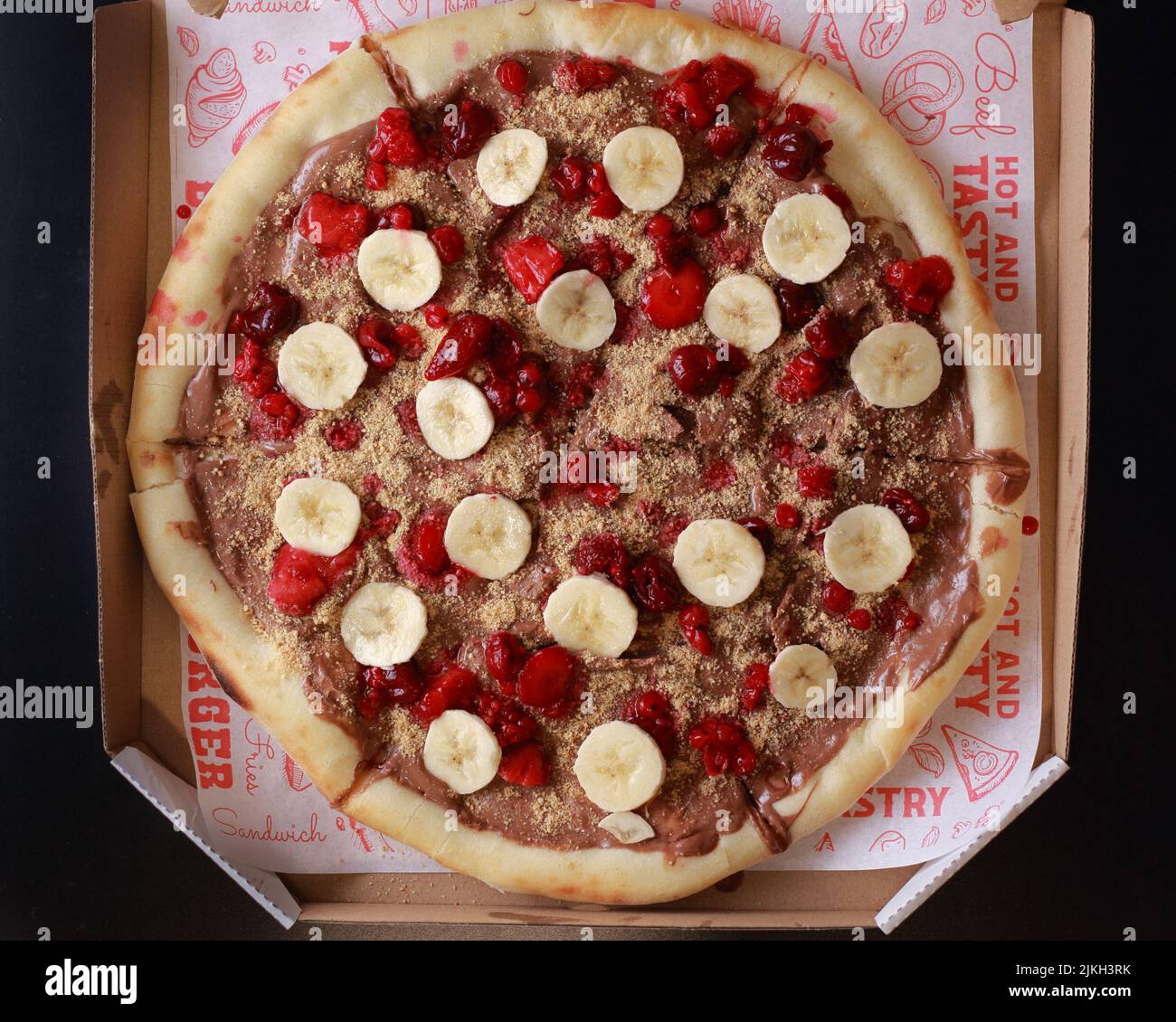 A top view of a chocolate spread covered pizza dough with banana ...
