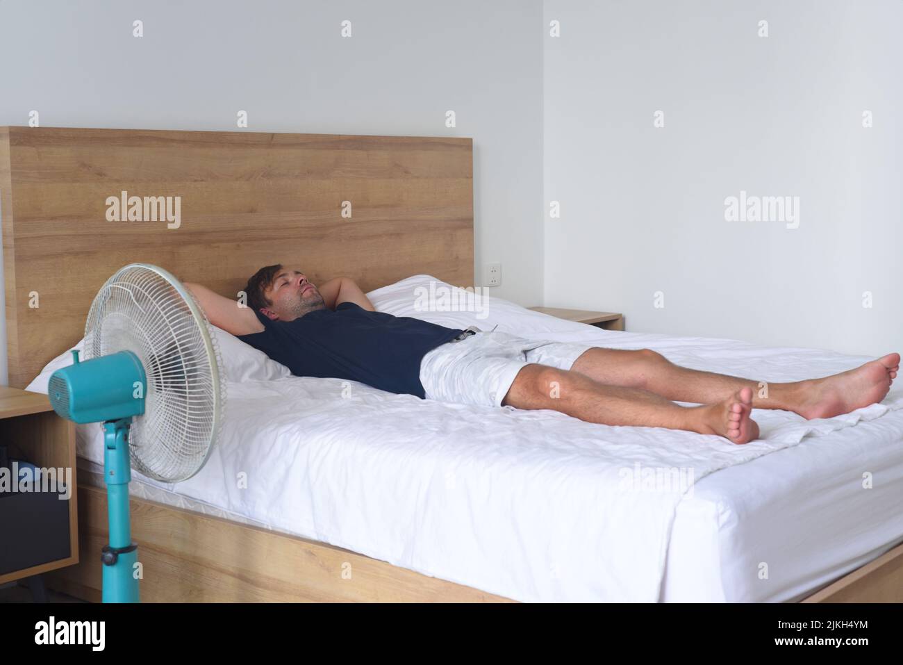 Man sleeping on a bed with fan Stock Photo - Alamy