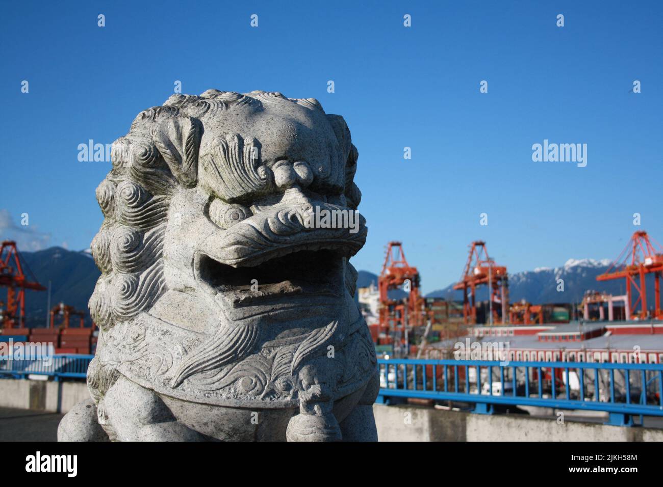 The Chinese lion sculpture with a the mountains and cranes in the Port ...