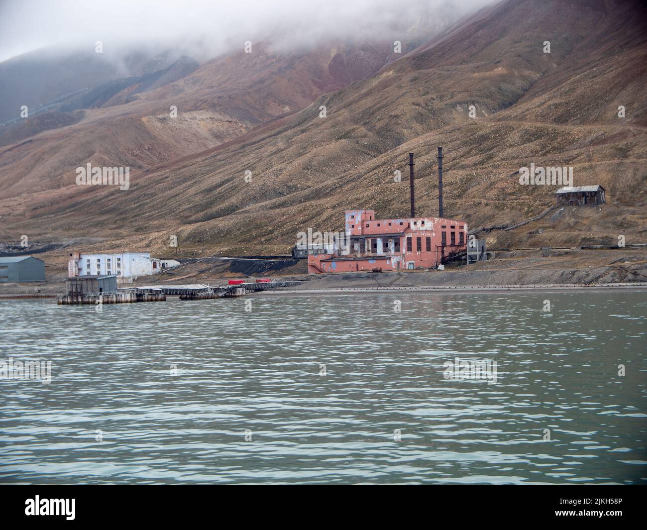 A view of abandoned soviet coal mining and a lake in the foreground in ...