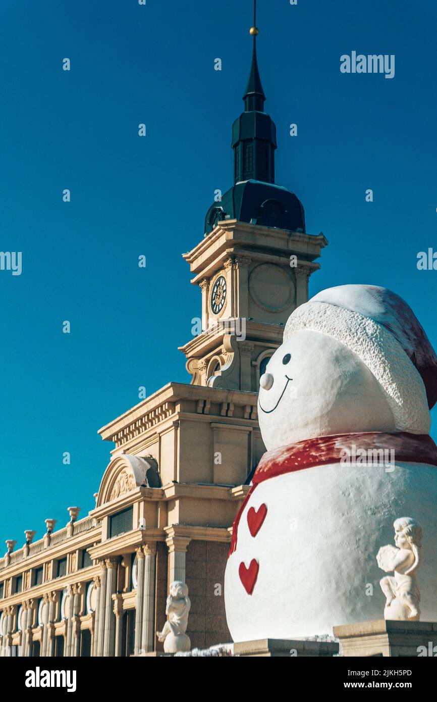 A side shot of a Gigantic snowman next to a city landmark of Harbin ...