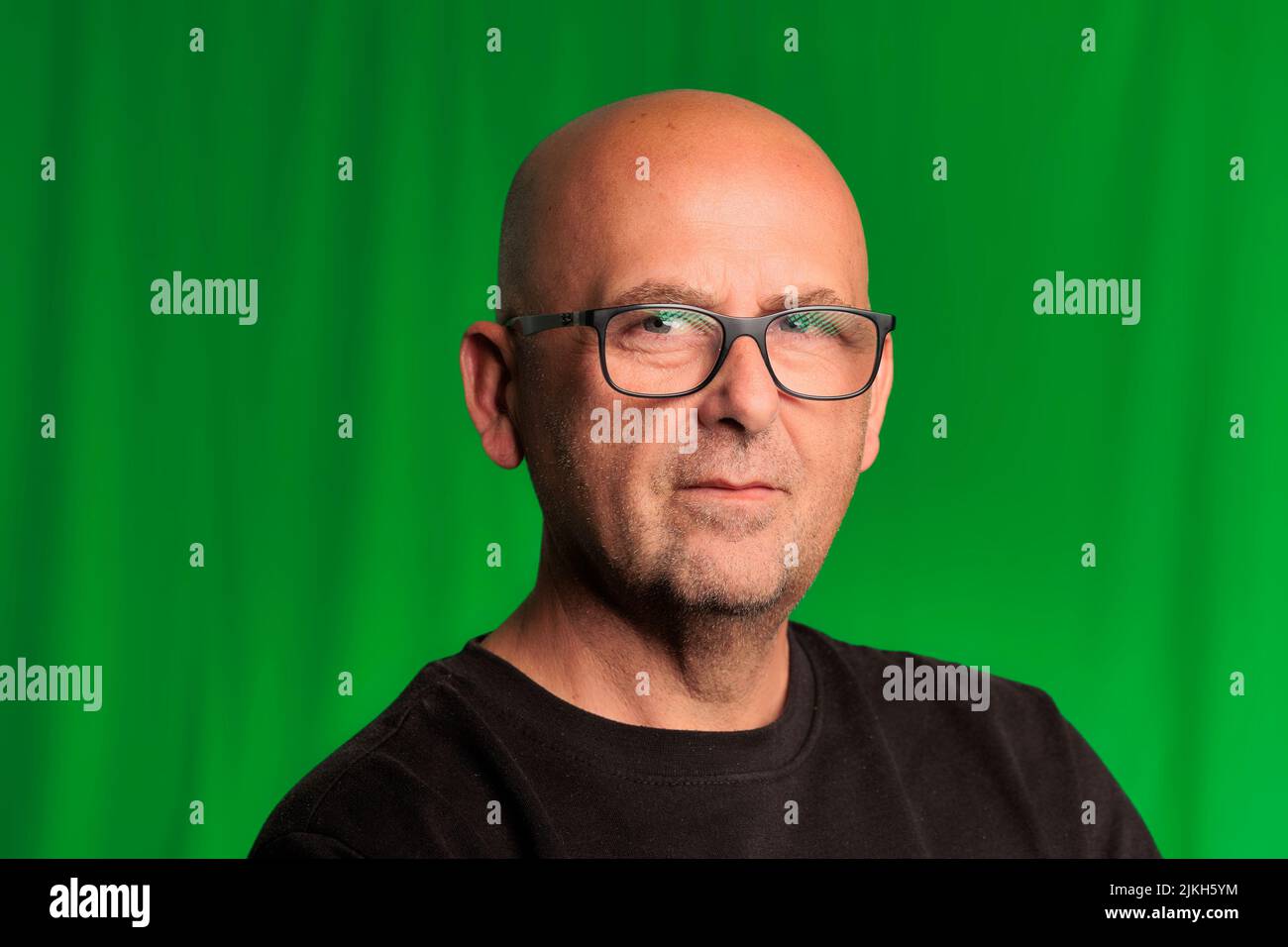 portrait bald man with glasses and green background Stock Photo - Alamy