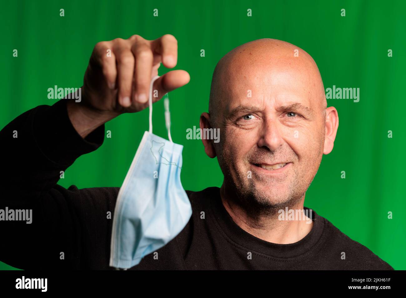 portrait bald man with glasses and green background with covid mask ...