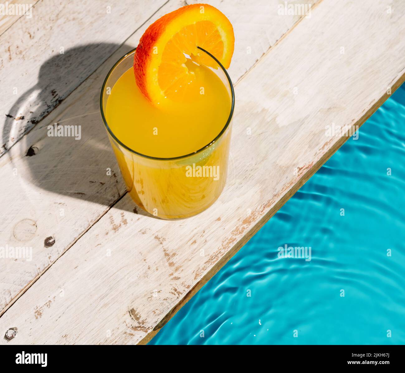 A high angle shot of a cup of orange juice with orange slice next to ...