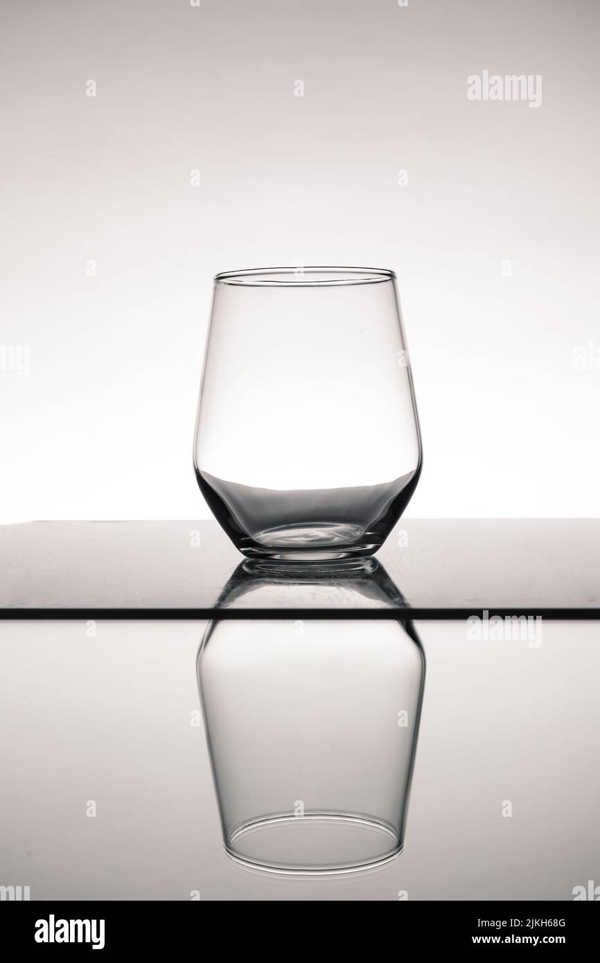 A grayscale shot of empty glass with the reflection on table Stock ...