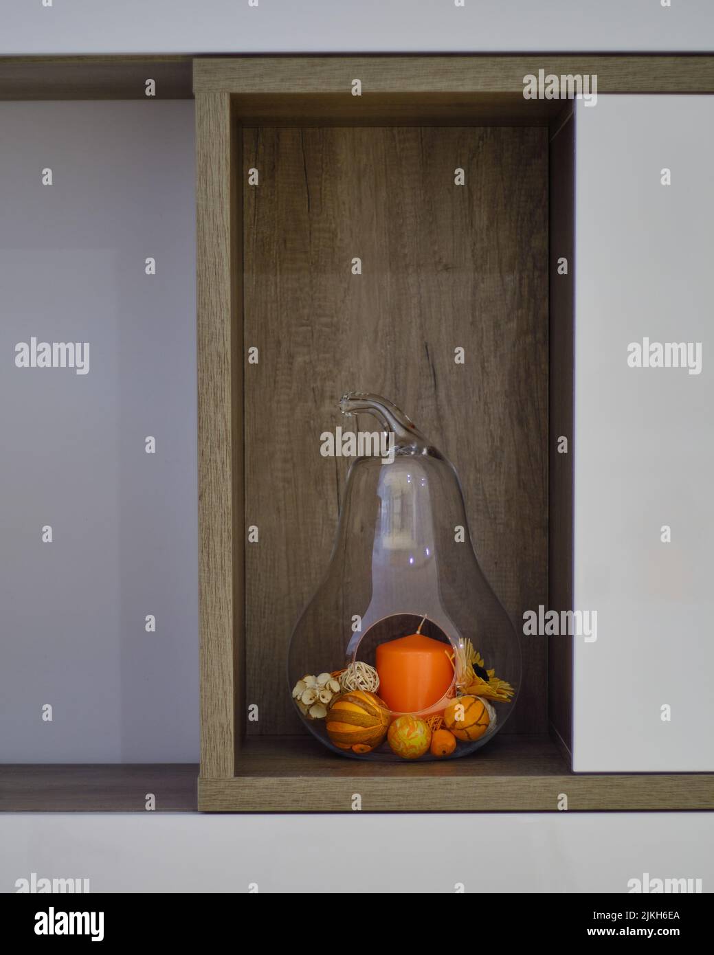 A vertical shot of a pear-shaped glass vase with candles and ...