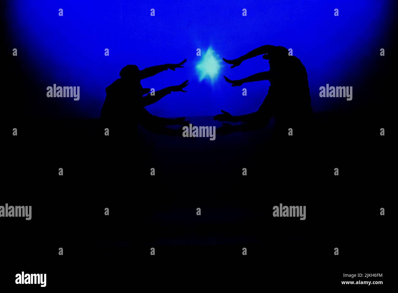 The silhouettes of people making shapes against a backlit screen Stock ...